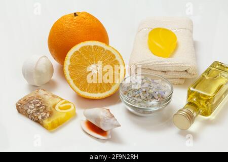 Cut orange with whole one, towel, bottle with aromatherapy oil and sea ...