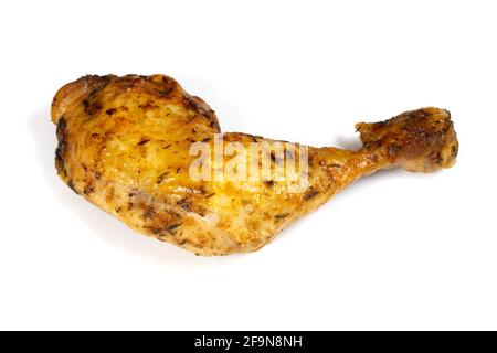 Golden roasted chicken leg on white plate surrounded by green onions ...