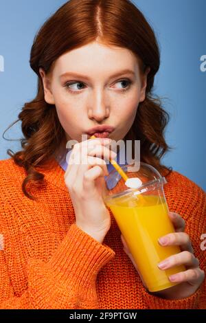curly young woman pouting lips and touching santa hat isolated on blue ...