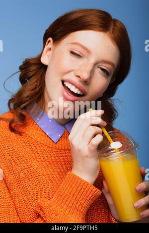 winking redhead woman with curly hair on blue background. Woman ...