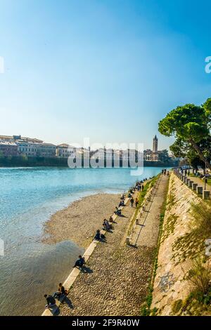 Promenade riverside in Verona, Italy. Back view of lady walking along ...