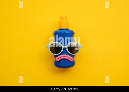Suncream lotion bottle with a sad face and sunglasses. Summer sunburn ...