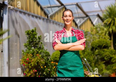 Female commercial gardener in front of the green house nursery Stock ...