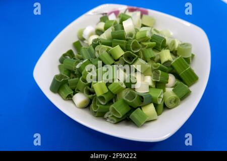 Closeup shot of a plate with chopped scallions isolated on a blue ...