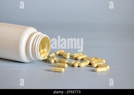 Medicinal capsules in gelatin shell spilled out of plastic jar. Medical ...