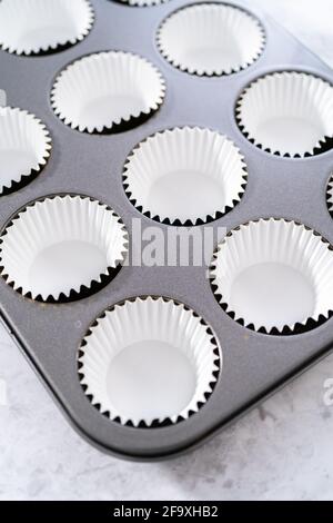Lining cupcake baking pan with foil cupcake liners to bake unicorn ...