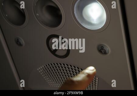 Passenger pressing the button to call cabin crew, stewardess for a ...