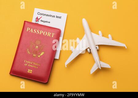 Toy plane, passport and coronavirus test results on yellow background ...