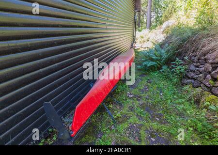 Close up view of red kayak at wet river coastline, stony slope, sunny ...