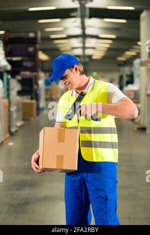 Warehouseman with protective vest and scanner, scans bar-code of ...