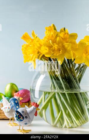 Easter themed yellow daffodils in round glass vase on table with light ...