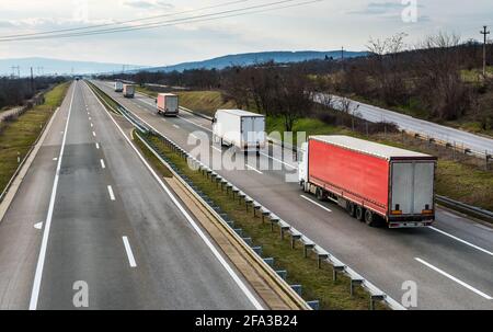 Convoy of Big Transportation trucks departing on a country highway ...