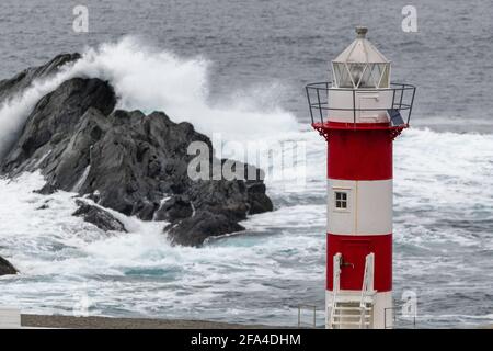 A tall circular lighthouse tower has horizontal red and white colors ...