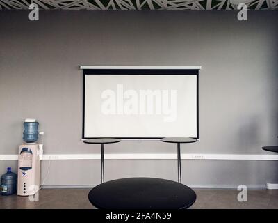 Projector screen canvas in modern conference room with big windows. Side view. Empty classroom ...