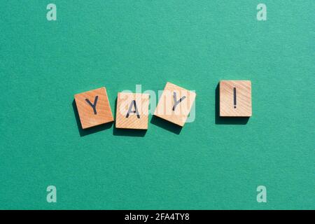 Yay, word in wooden alphabet letters isolated on bright pink background ...