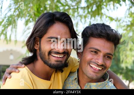 Portrait of a young cheerful Indian gay couple embracing and smiling in ...