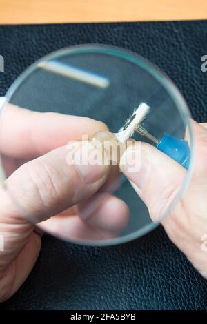 hearing aid acoustician at work, he is working on a hearing aid for ...