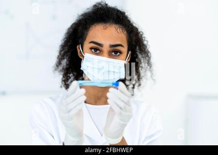 Researcher in protective mask holding test tubes with monkeypox ...