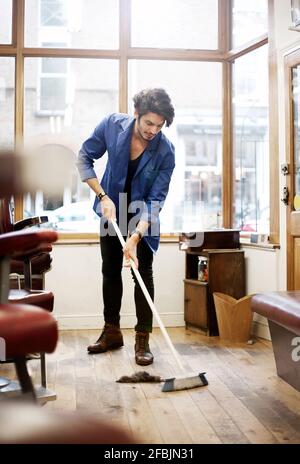 Hairdresser in barber shop sweeping up hair Stock Photo - Alamy