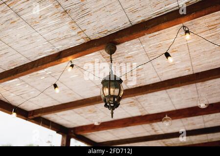 1-light metal chandelier under the ceiling made of bamboo and garland ...