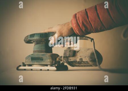 Man sanding wood plank using electric sand machine Stock Photo - Alamy