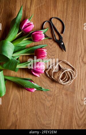 Floristic workplace with craft paper, twine Arranging pink tulips ...