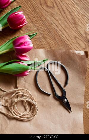Floristic workplace with craft paper, twine Arranging pink tulips ...