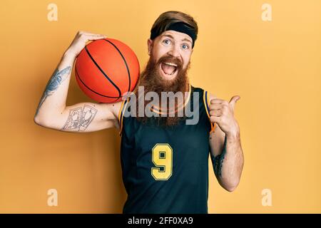 redhead basketball player holding ball and looking at camera near fence ...