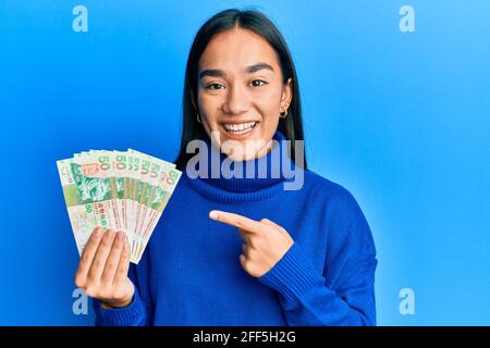 Young brunette woman holding hong kong 20 dollars banknotes smiling ...