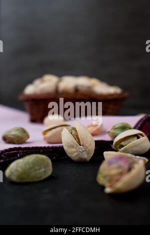Some pistachios in a basket on a black wooden table Stock Photo - Alamy
