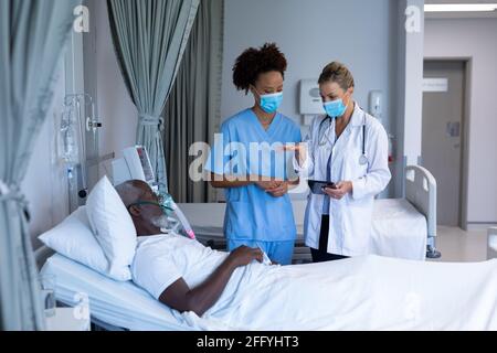 Two diverse female doctors talking to african american male in hospital ...