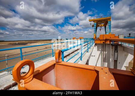 Shardara river dam. Concrete bridge, gentry crane. Orange weights in ...