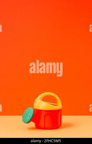 A row of colorful watering cans on a fence against a blurred background ...