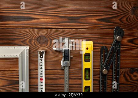 Level and corner, ruler and caliper, wooden background, top view ...