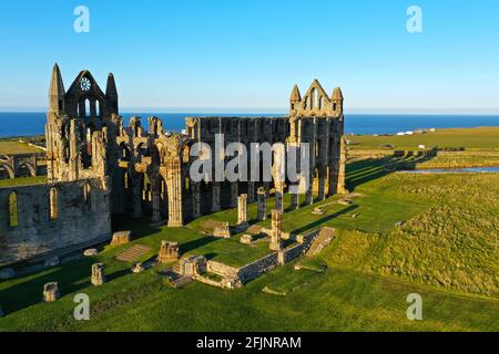 Aerial view of Whitby Abbey ruins, a town with a harbor, green fields ...
