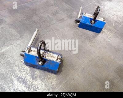 Pair of blue industrial lifting magnets on flat sheet metal surface ...