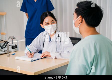 Asian woman writing notes in journal with laptop computer at home ...