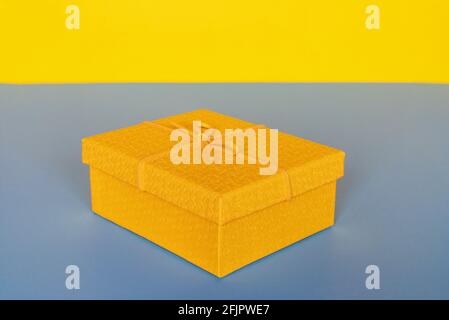 Yellow gift box on blue and yellow background with copy space for text ...