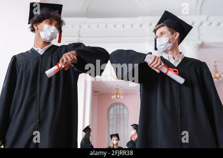 Low angle view of interracial bachelors throwing caps near university ...