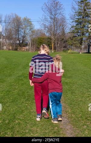 Sister hugging her brother from behind, smiling at camera, portrait ...