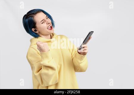 A female in yellow hoody holding wireless earphones. The white ...