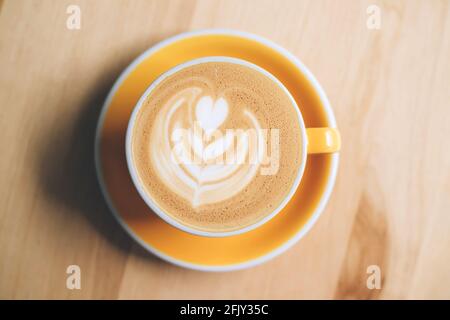 Cappuccino with frothy foam, yellow coffee cup top view is on the ...
