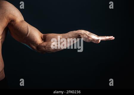 tense arm, veins, bodybuilder muscles on a dark background, isolate ...