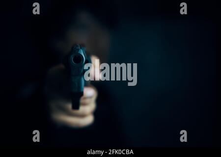 Threat of firearms. Muzzle of gun in man's hand is pointed at camera ...