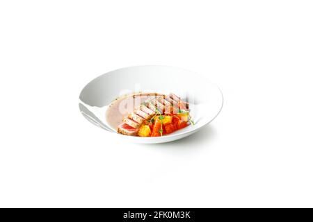 Cooked juicy tuna steak with vegetables on a white plate on a white ...