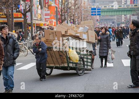 Japanese male pulls heavy cart containing cardboard through ...