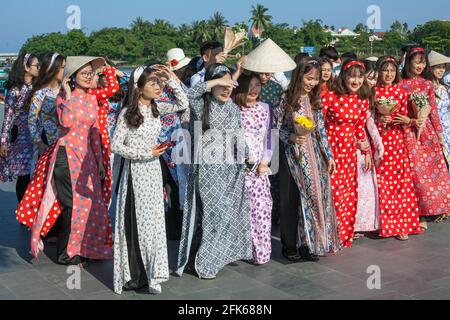 Group of pretty Vietnamese females wearing traditional Ao Dai posing by the riverside in the old ...