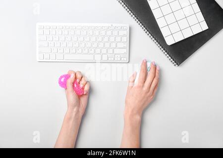Woman squeezing antistress ball while working on computer in office ...