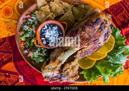 Roasted meat with vegetables and refried beans on colorful tablecloth ...
