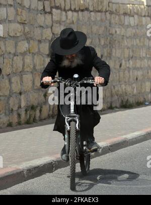 An Orthodox Jewish man on a bicycle shopping at the Mahane Yehuda ...